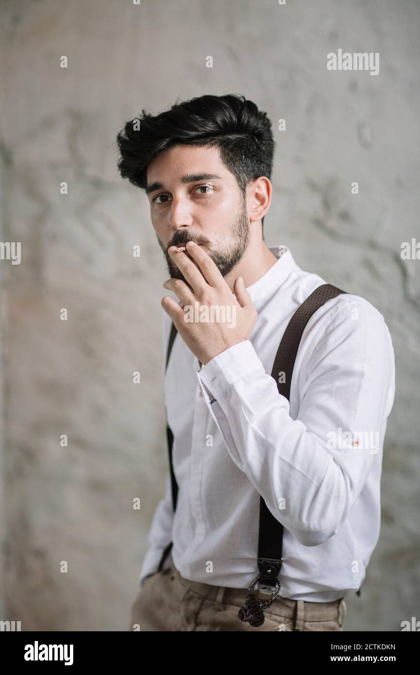 Man smoking while standing against wall Stock Photo - Alamy