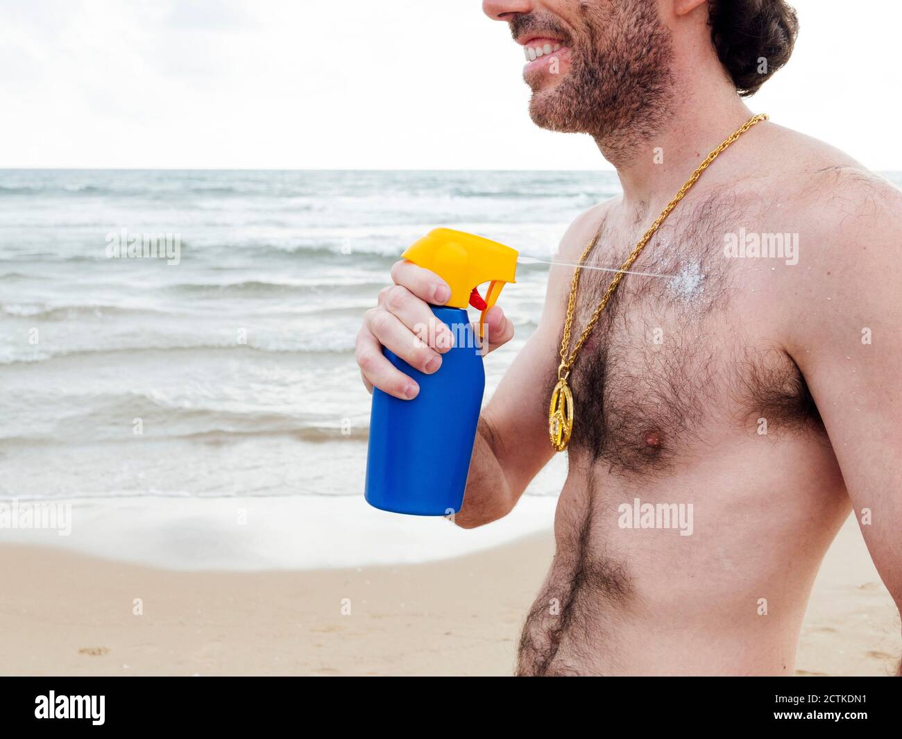 Smiling man applying suncream at beach Stock Photo - Alamy