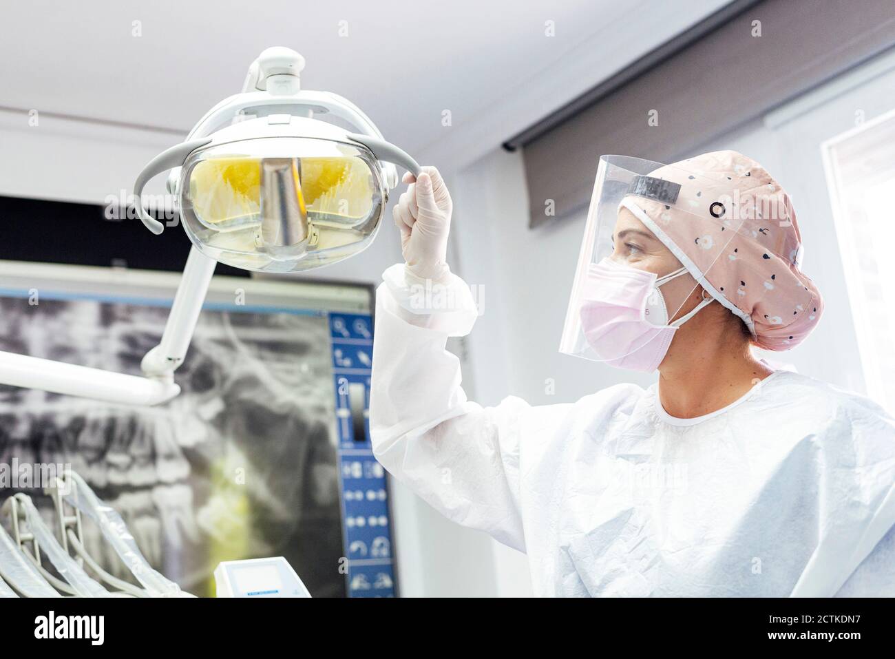 Doctor in protective workwear adjusting electric lamp in clinic Stock ...