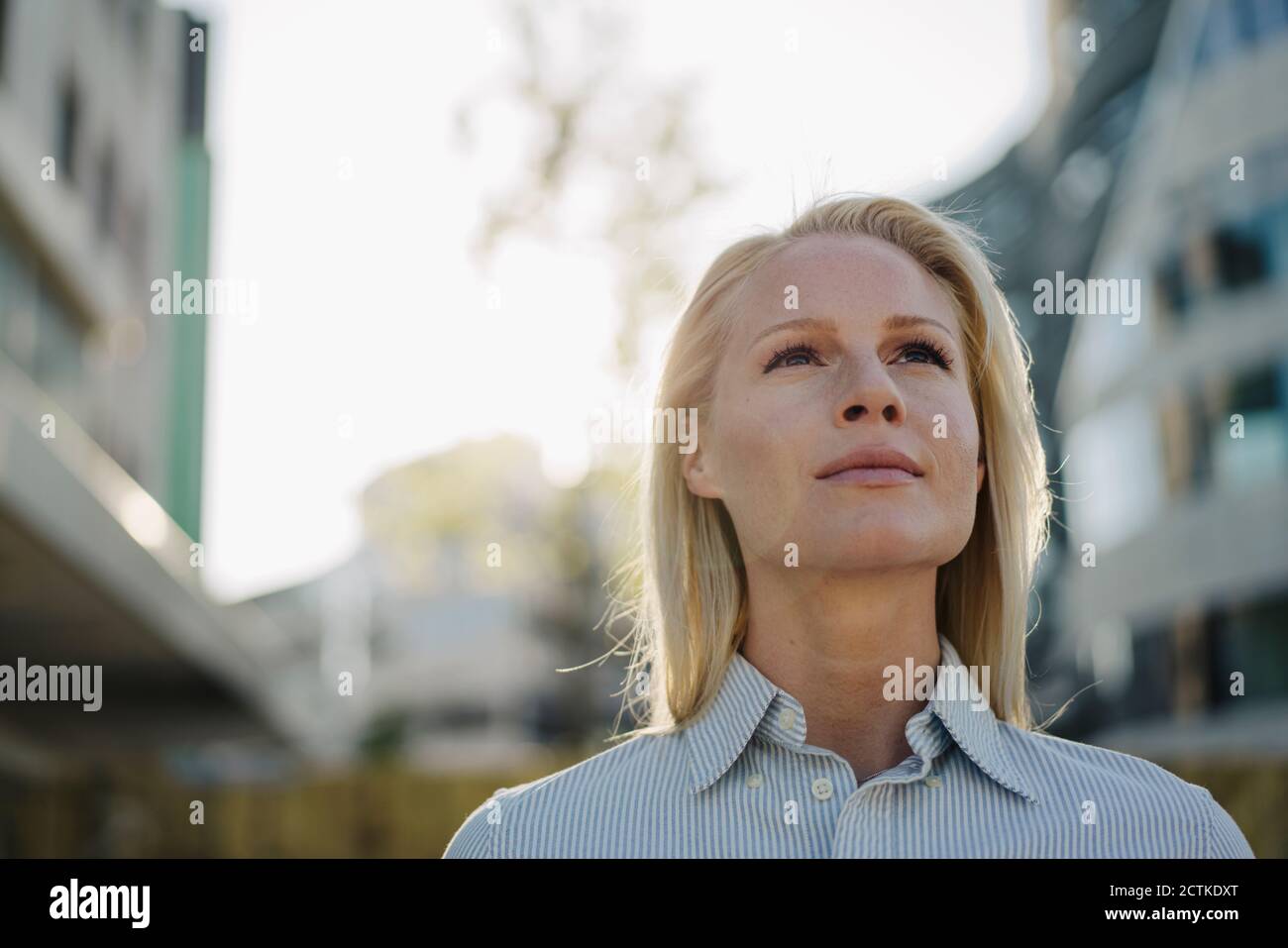 Close-up of thoughtful blond female entrepreneur looking up at ...