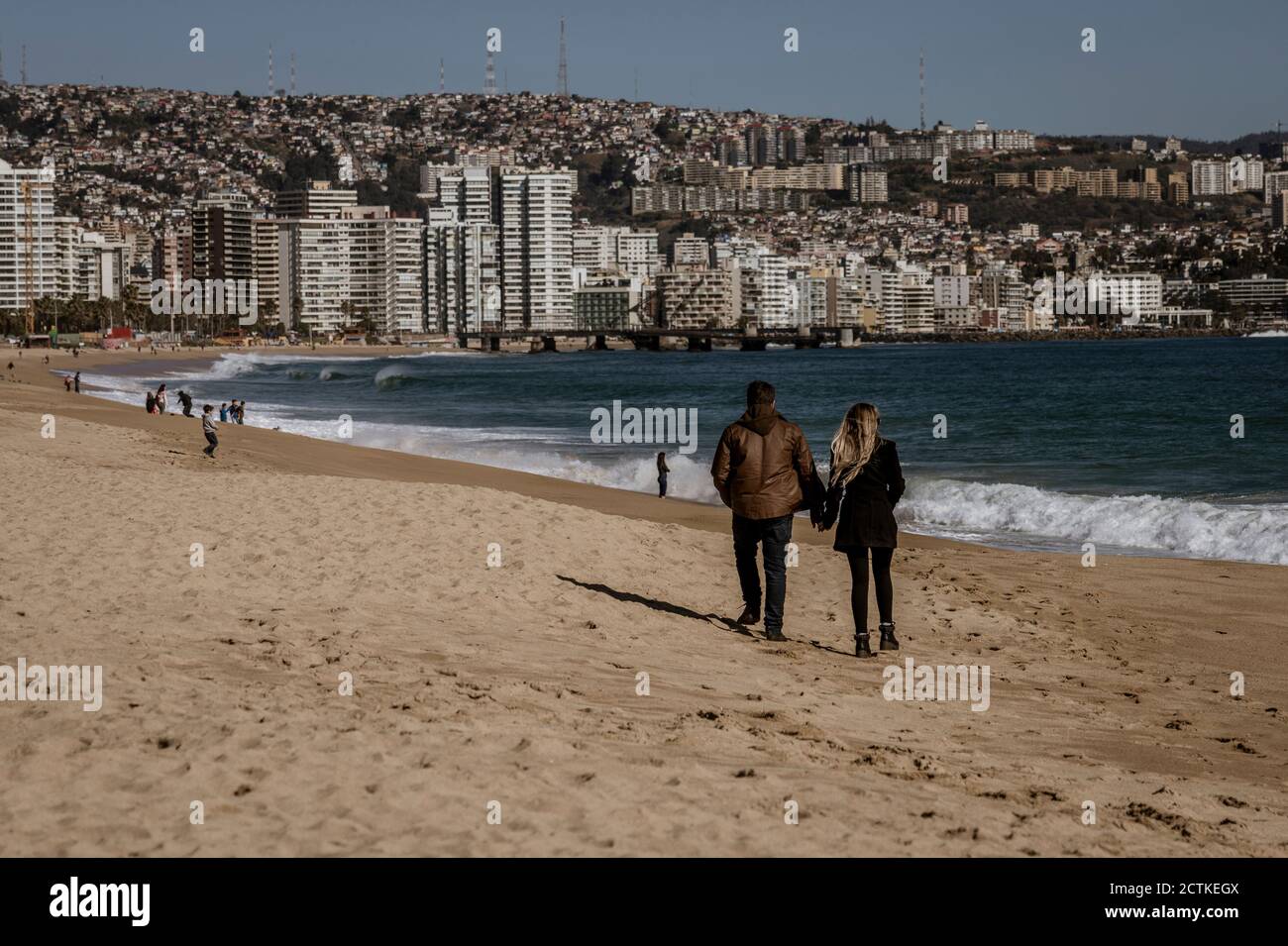 Valparaiso, Chile - 2019-07-30 - Two people walk along the beach with ...