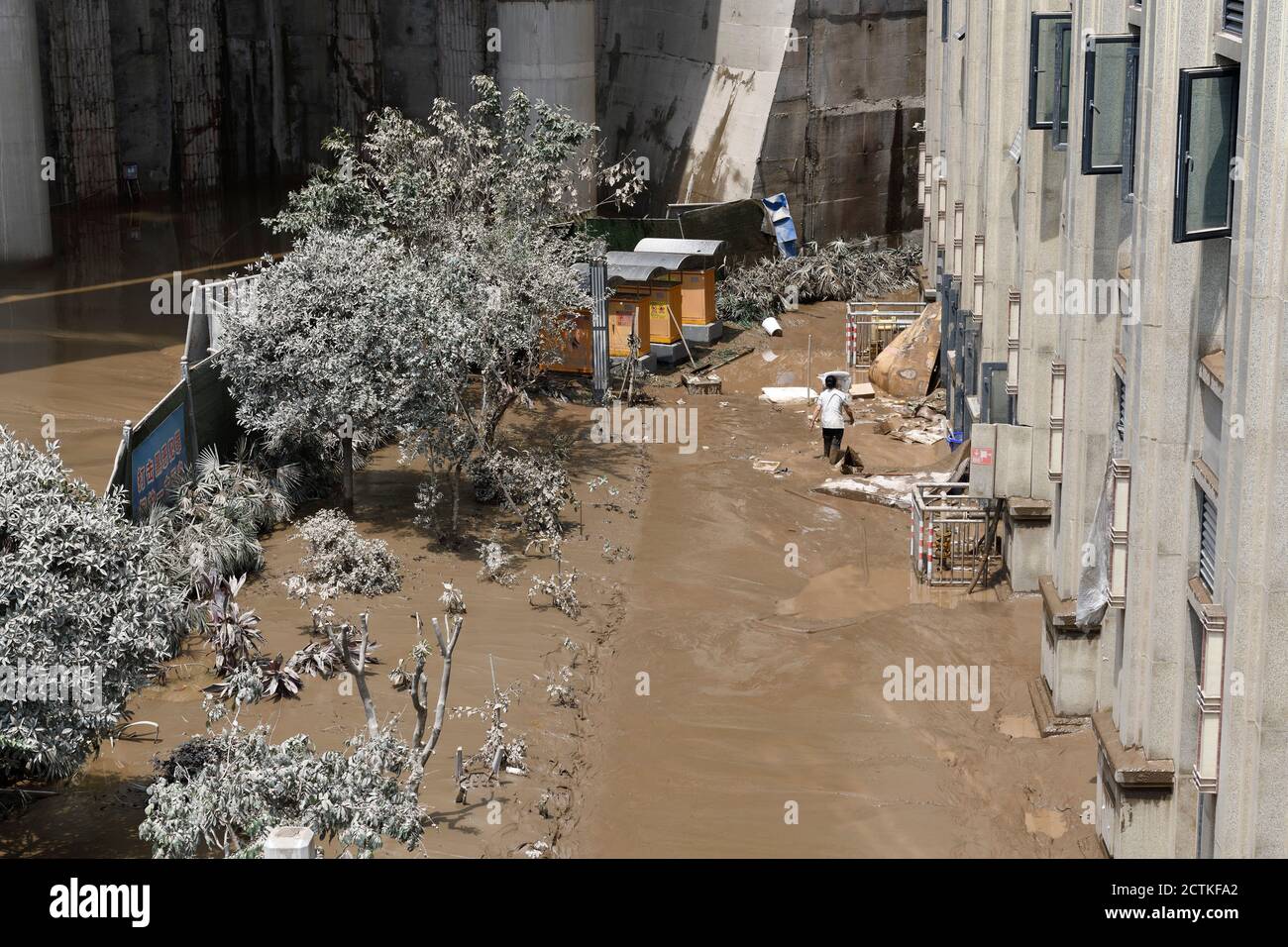 A person walks in through silt and mud due to flood in Chongqing, China ...