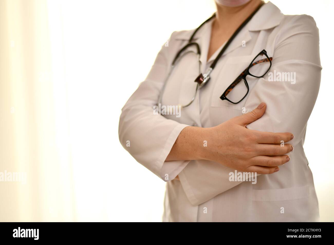 The doctor in a white robe facing the light, hands with a stethoscope ...