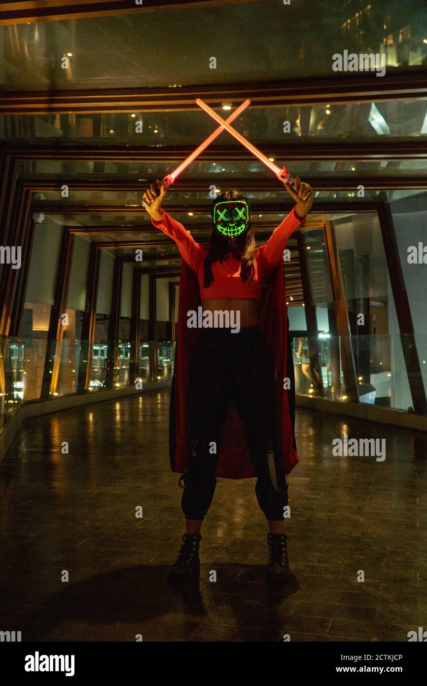 Green neon mask figure, with red light sabers wearing cloak, in dark ...