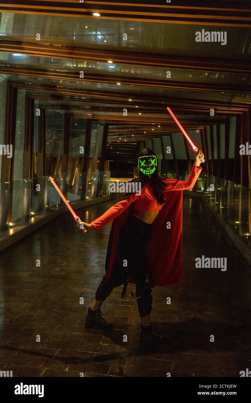 Green neon mask figure, with red light sabers wearing cloak, in dark ...