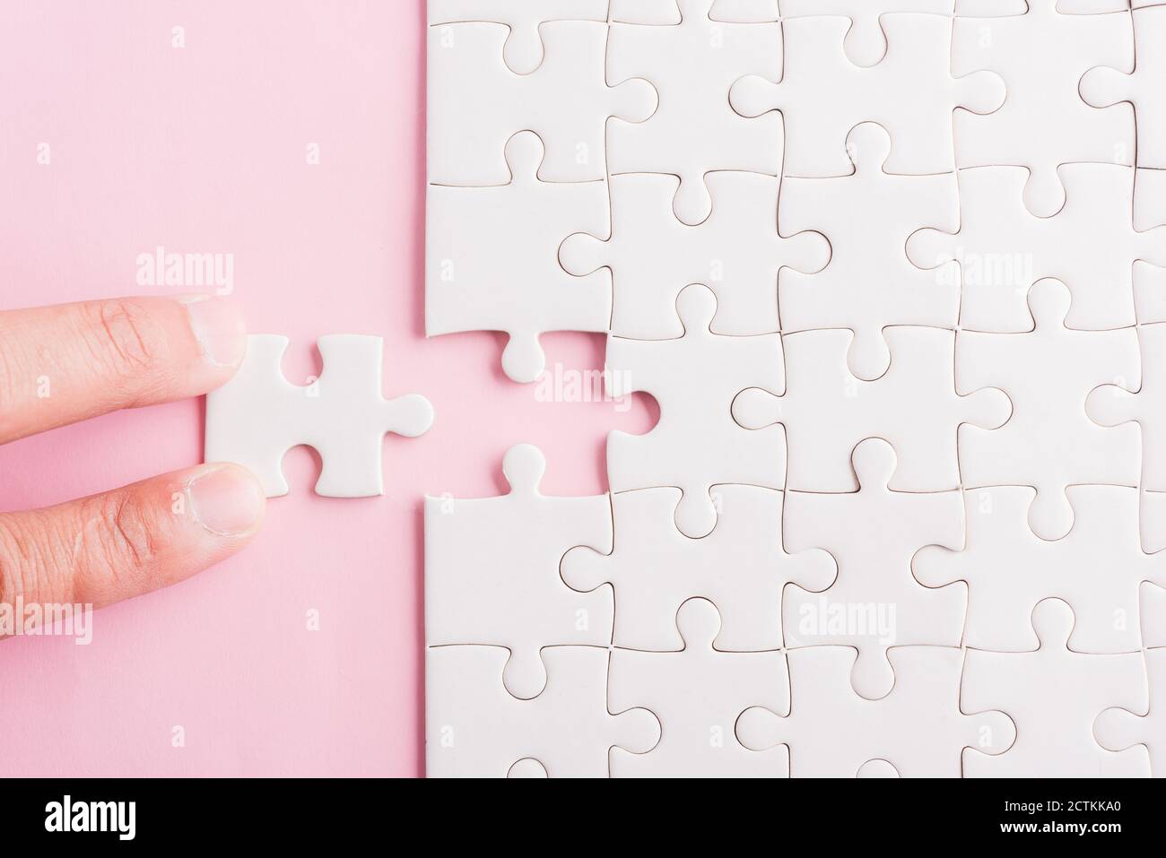 Top view flat lay of hand-holding last piece white paper jigsaw puzzle ...