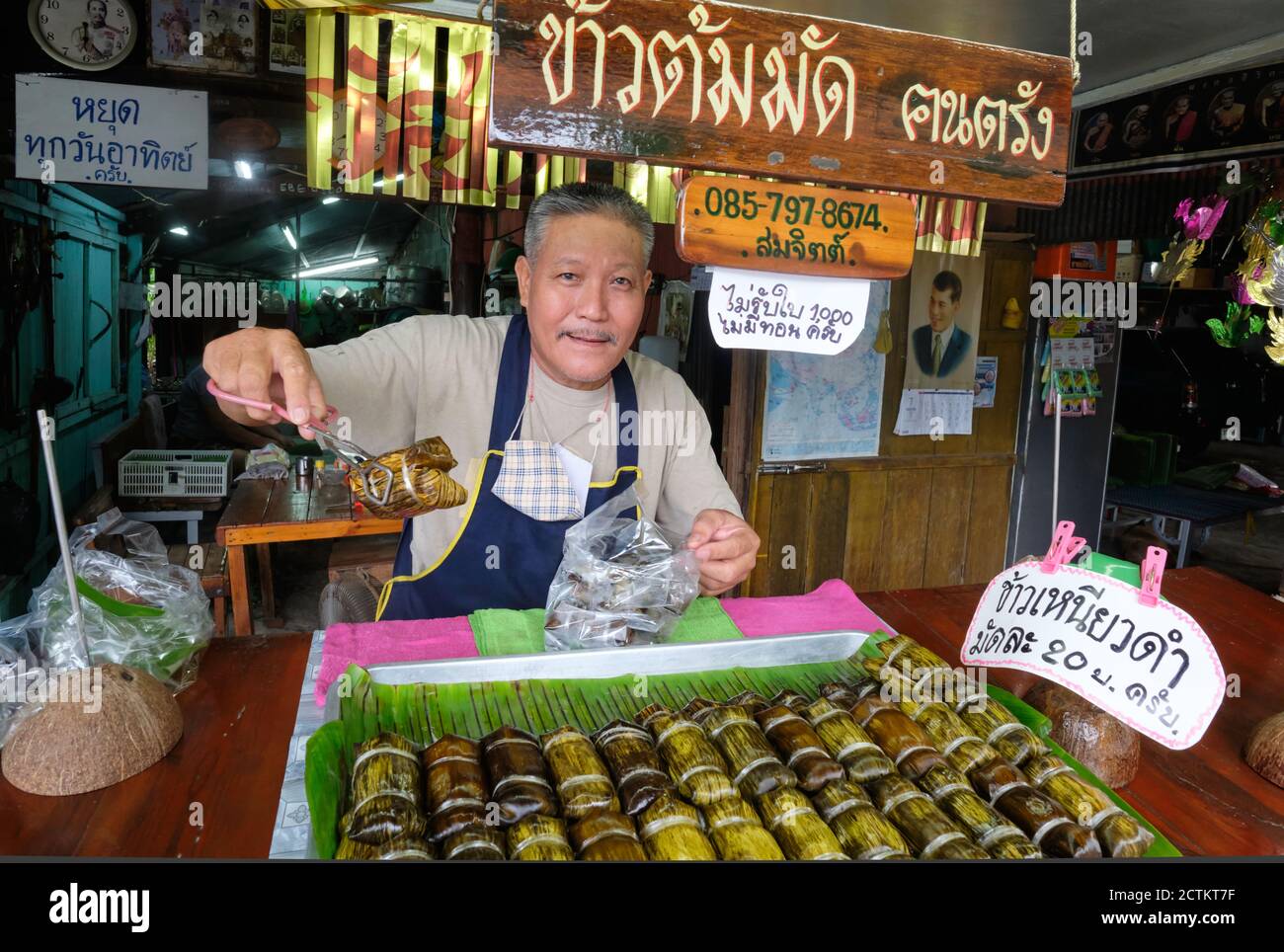 A vendor holds up Khao Thom Mad (Mat) wrapped in pandanus leaf, a ...