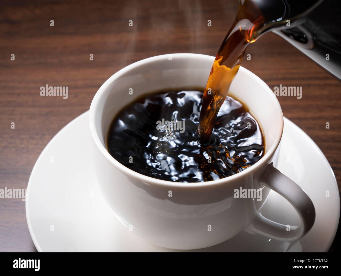 Pouring hot coffee against a dark wooden backdrop Stock Photo - Alamy