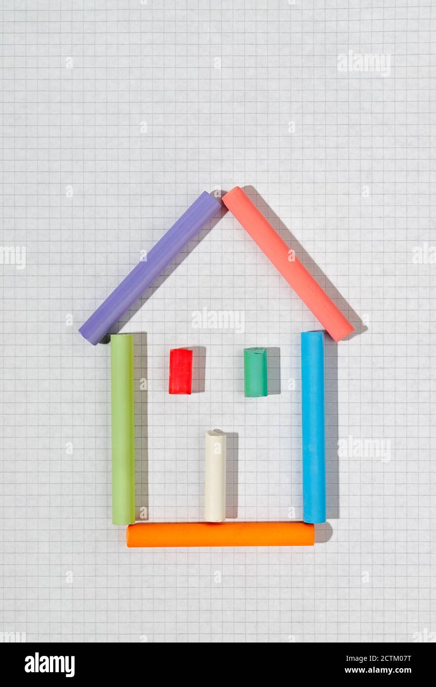 Colorful house shape with different pieces of chalk on white squared ...