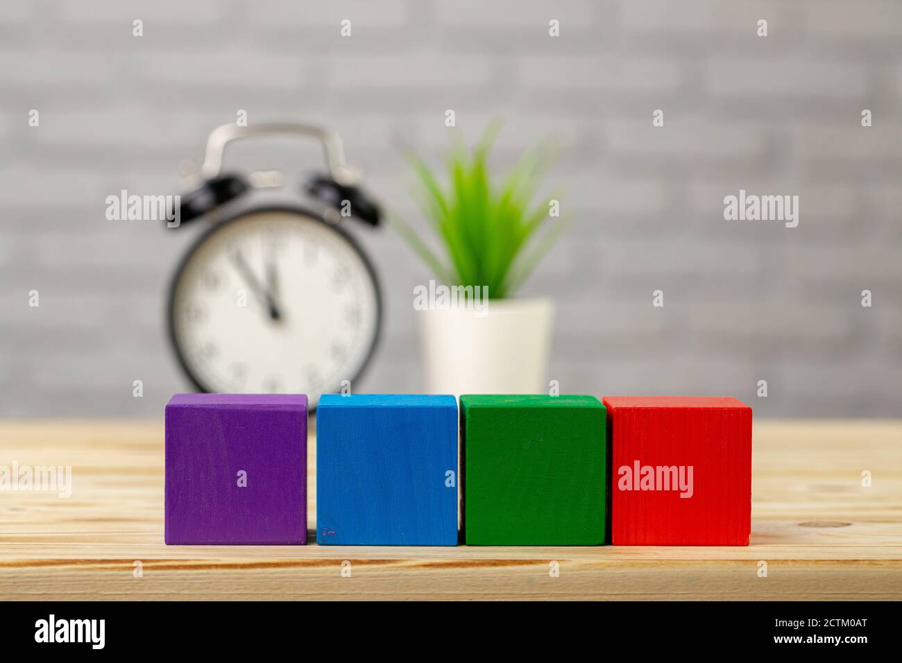 Wooden blocks and alarm clock on wooden desk Stock Photo - Alamy