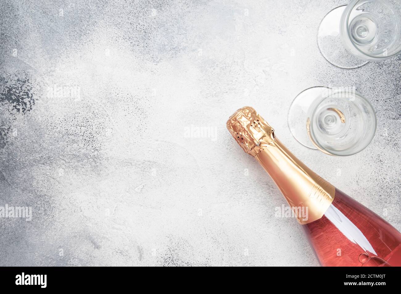 Bottle with pink sparkling wine or rose champagne and glasses, gray ...