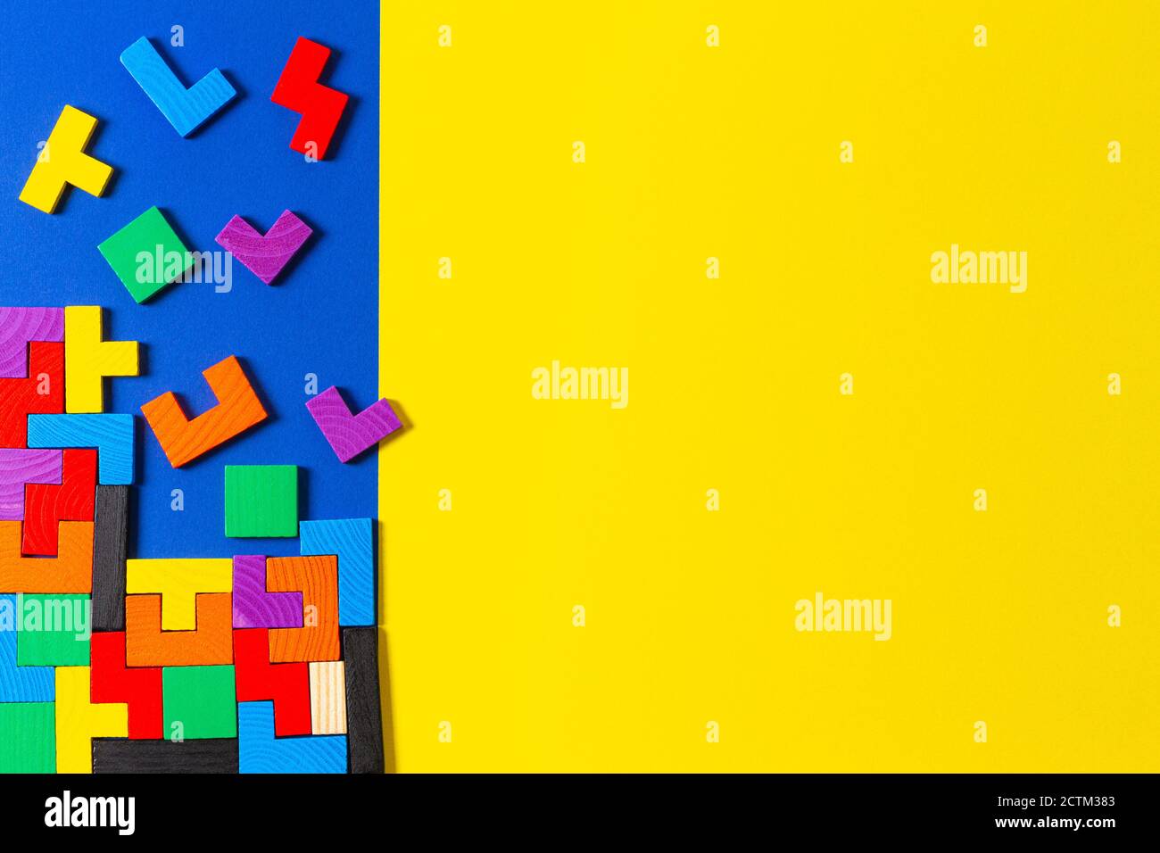 Different colorful shapes wooden puzzle blocks on blue and yellow ...