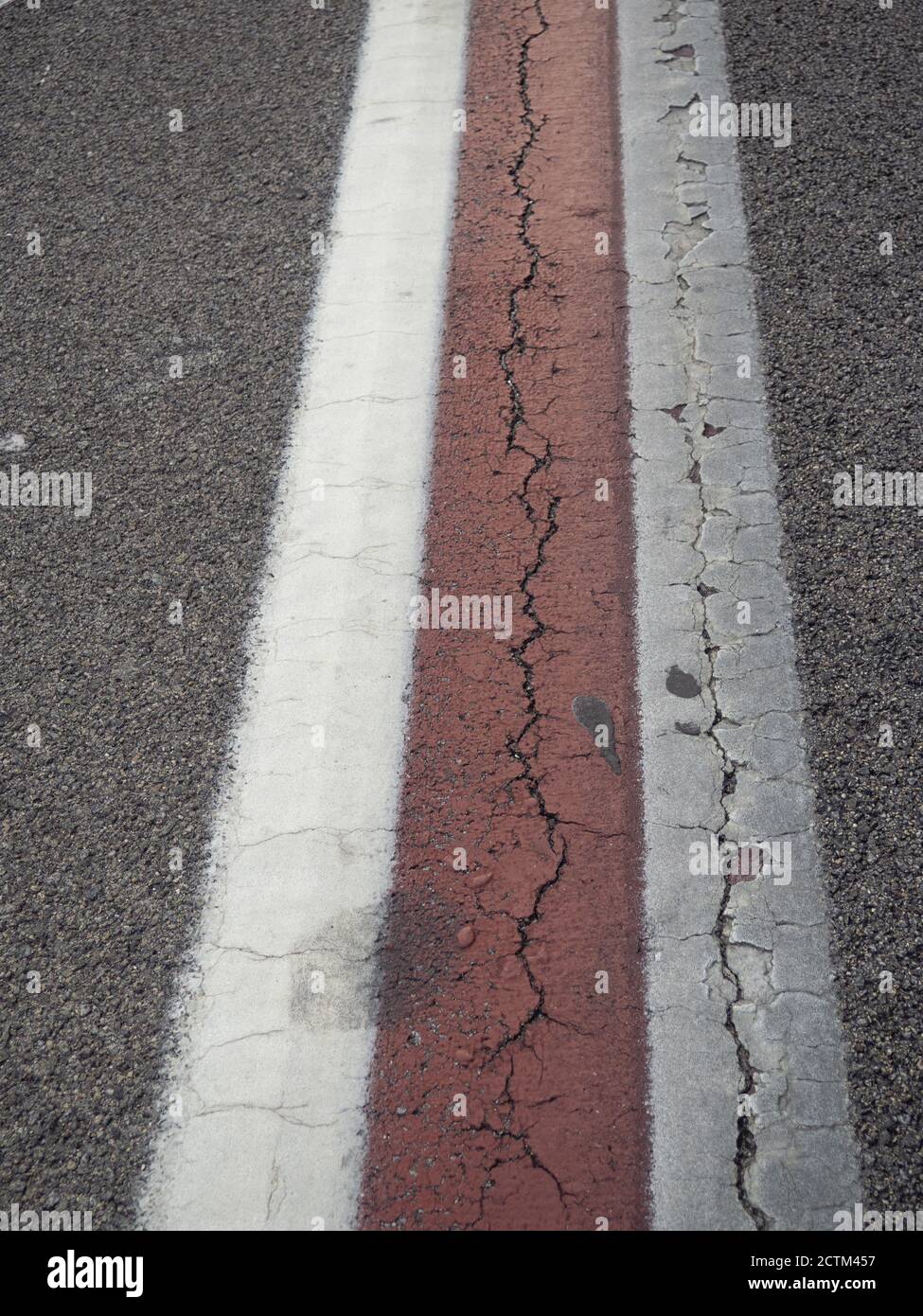 Vertical closeup shot of white and red line on the asphalt of a road ...