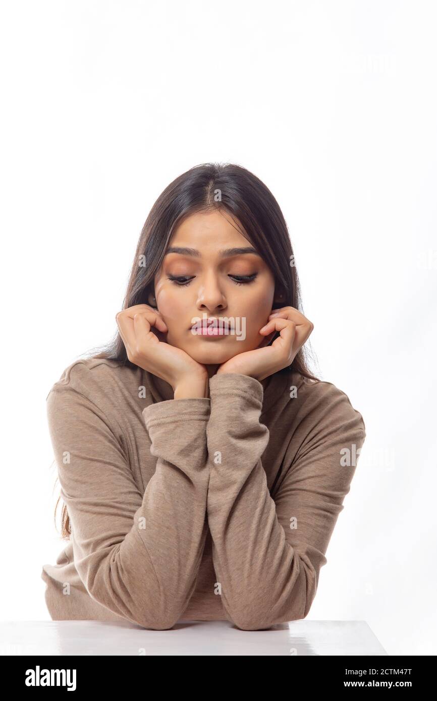 Young woman looking downwards with her face resting in her hands Stock ...