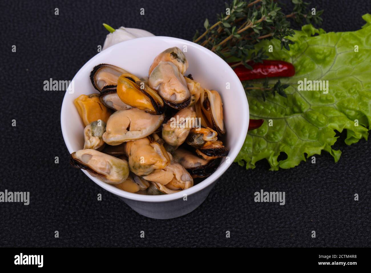 Pickled mussels in the bowl served pepper, garlic and salad leaves ...