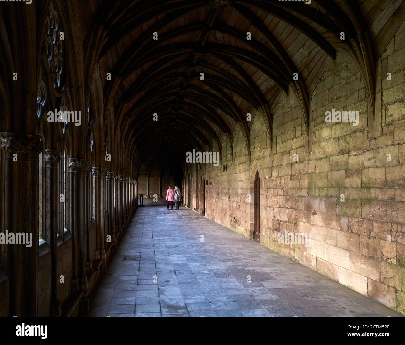 A couple walk along a corridor of the cloisters at the medieval ...