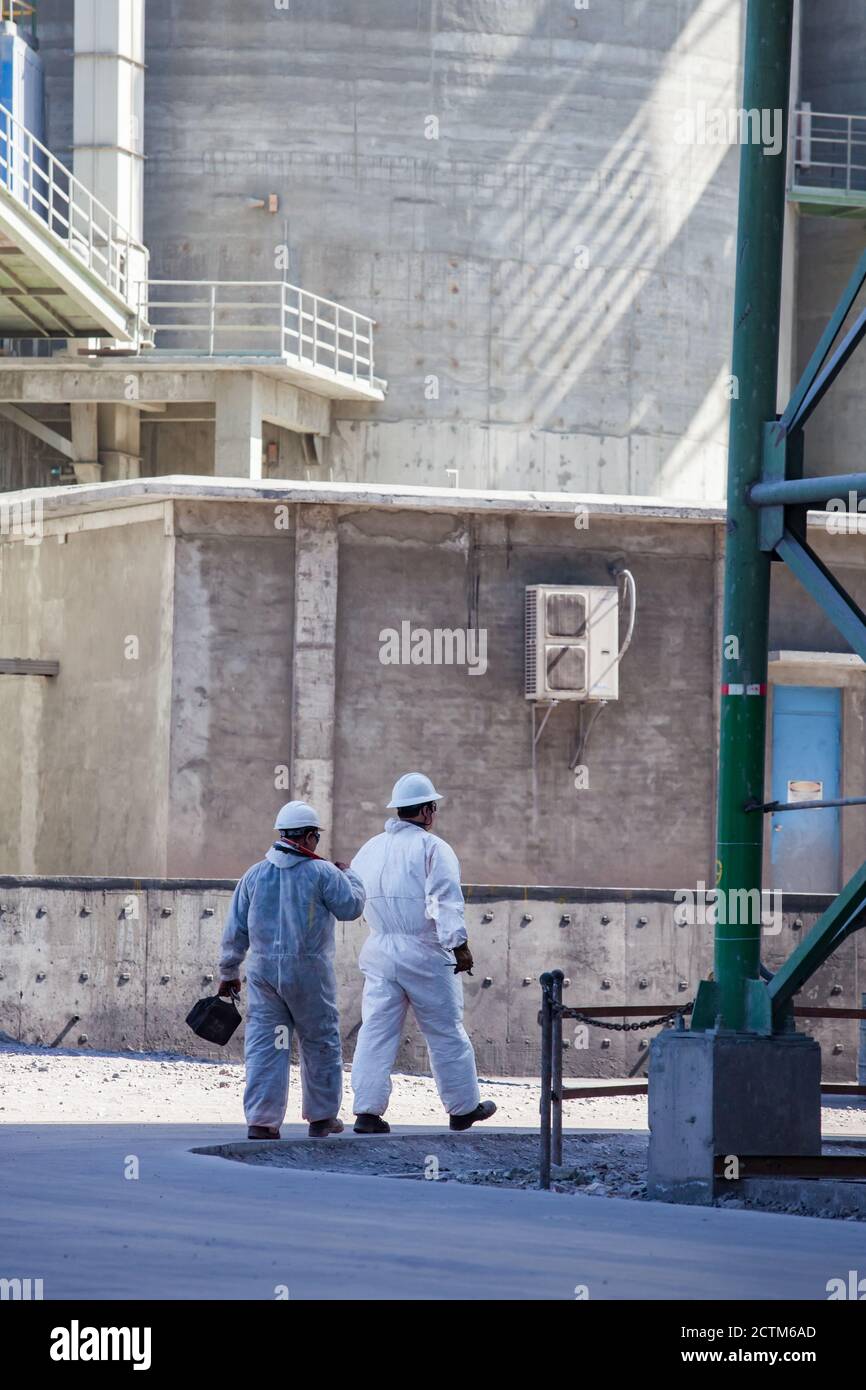 Two workers in white helmets and white protective suits with tools. On ...