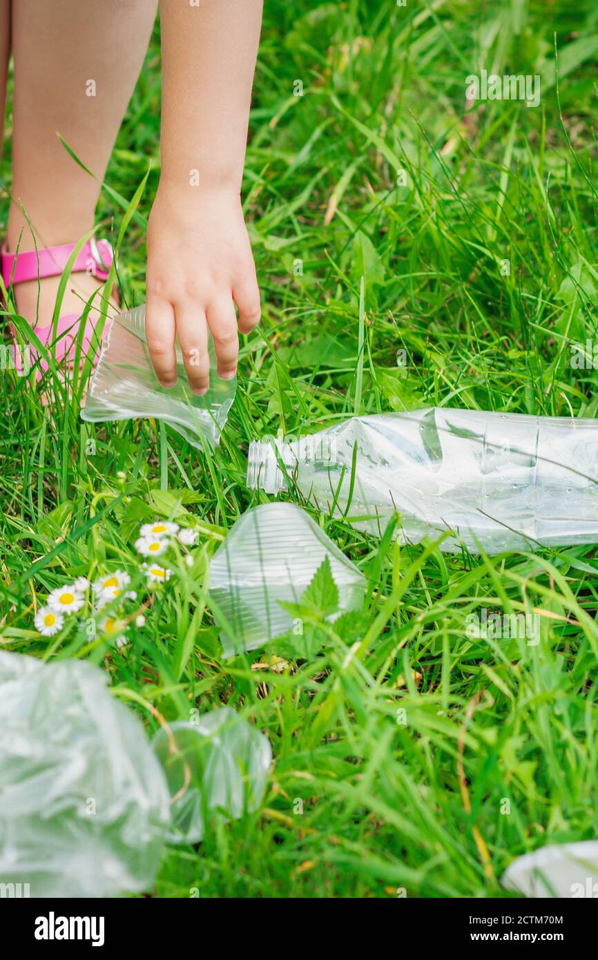 Hand of child cleans green grass from plastic trash in the park Stock ...