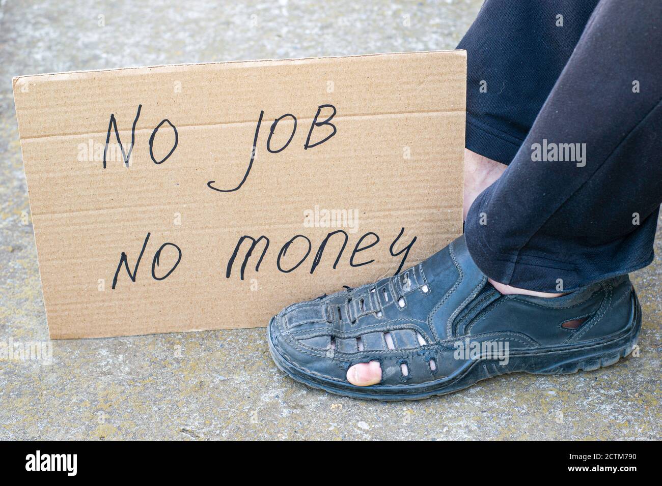 unemployment concept man in old torn shoes sits on the ground at his ...