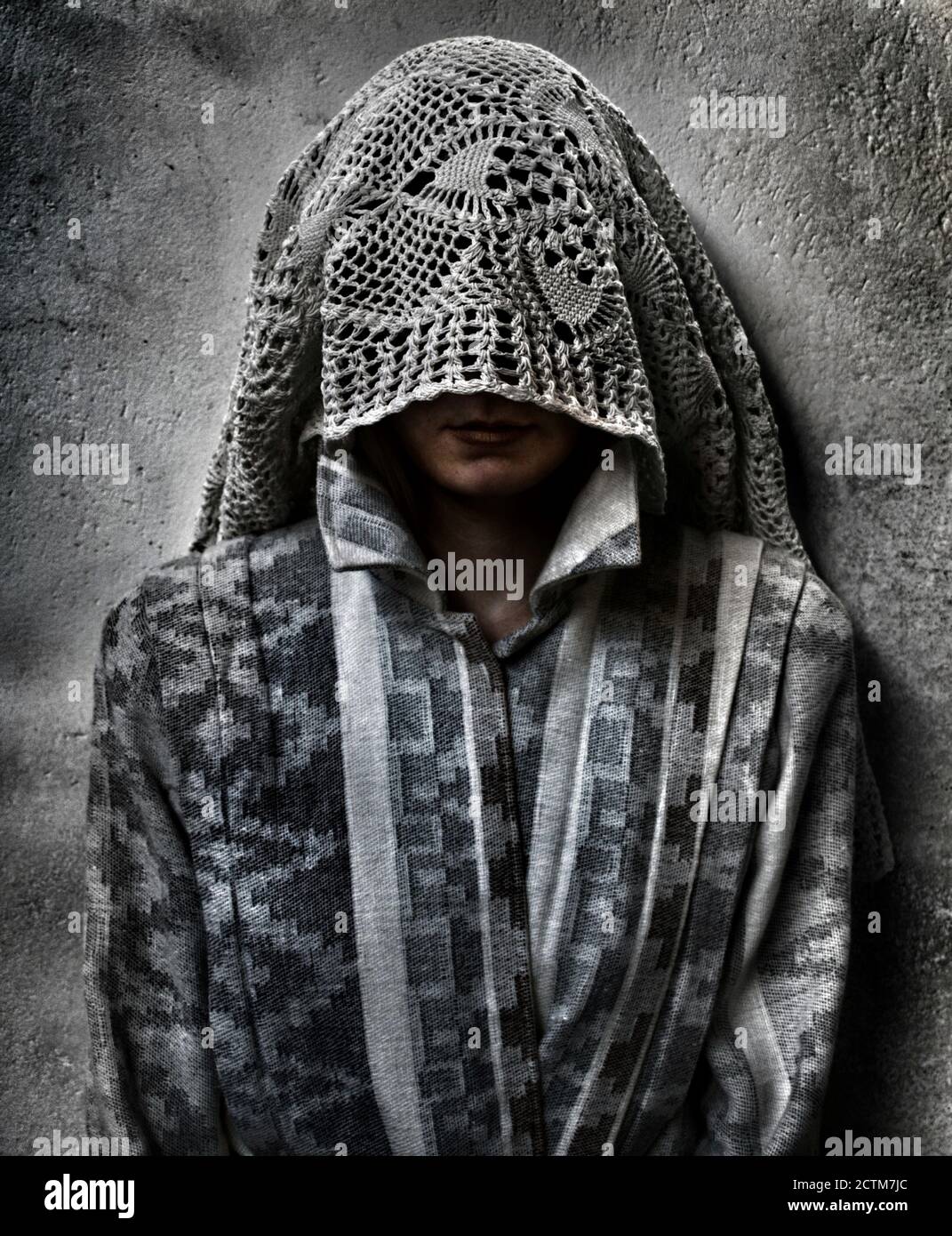 A mysterious, hooded woman standing against a wall Stock Photo - Alamy
