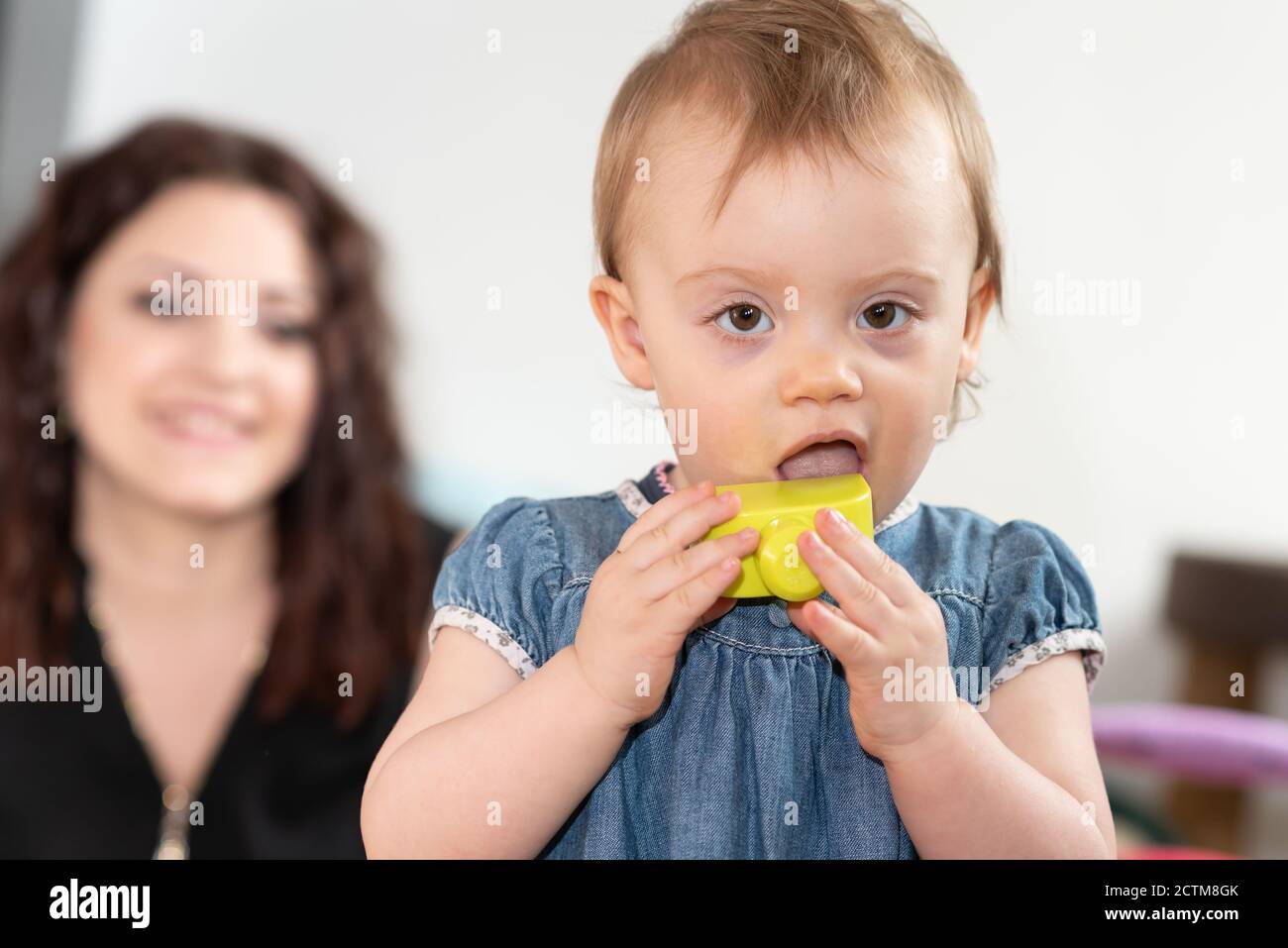 Cute baby girl biting a plastic toy and looking at the camera Stock ...