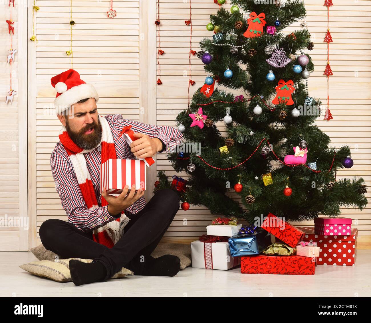 Santa Claus with disappointed face on wooden wall and red garlands ...