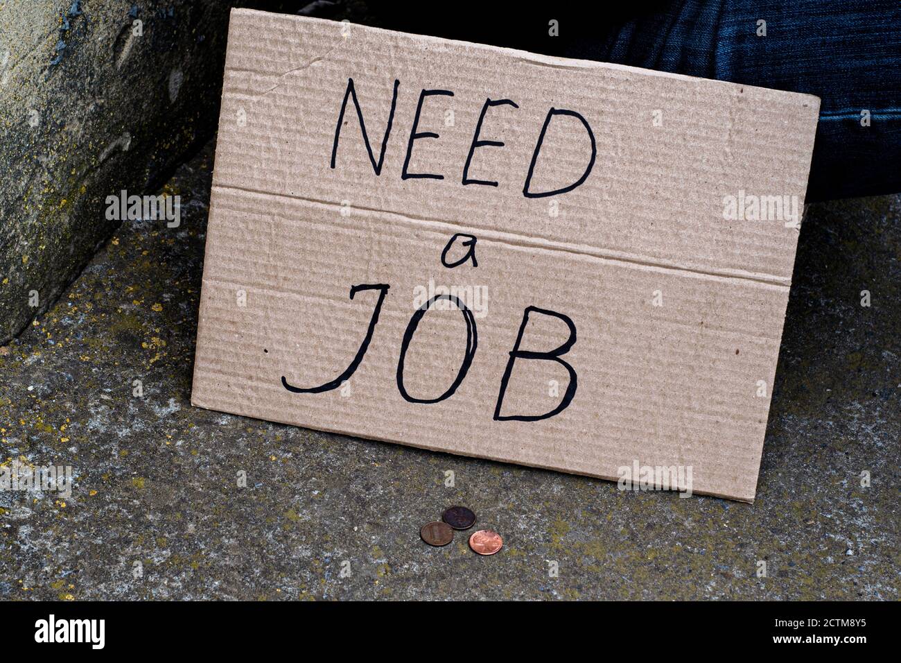 a cardboard tablet with the inscription need a job next to an ...