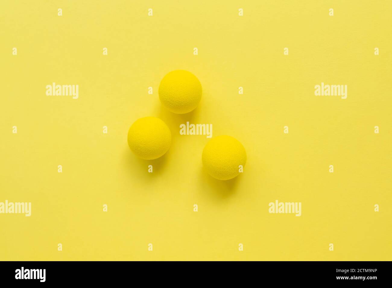 Three synthetic yellow balls on yellow background. Monochrome minimal ...
