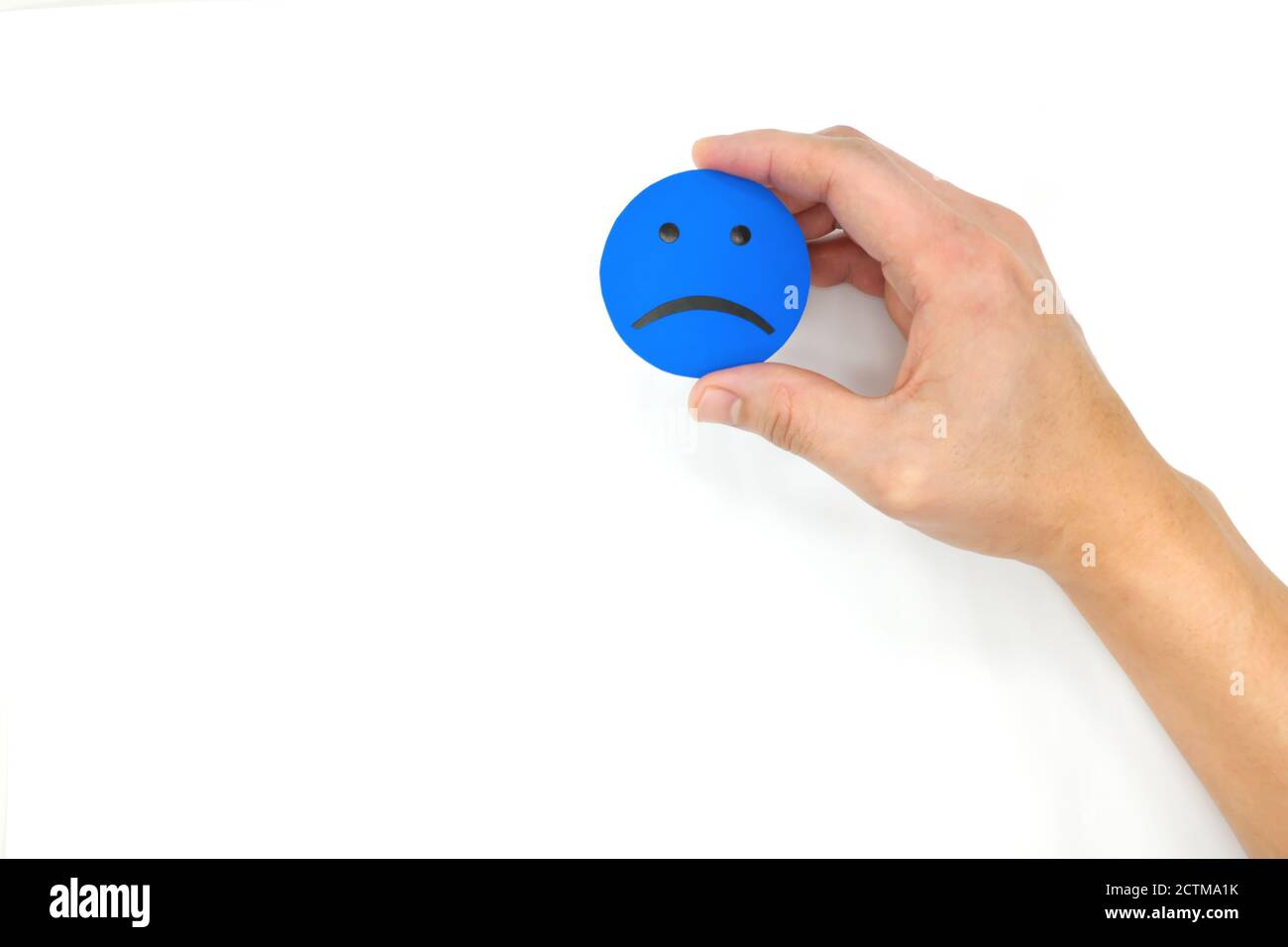 Hand holding a blue sad face icon in white background with copy space ...