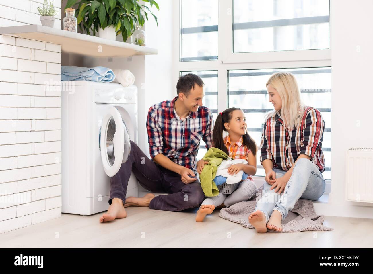 family mother, father and child girl little helper in laundry room near ...