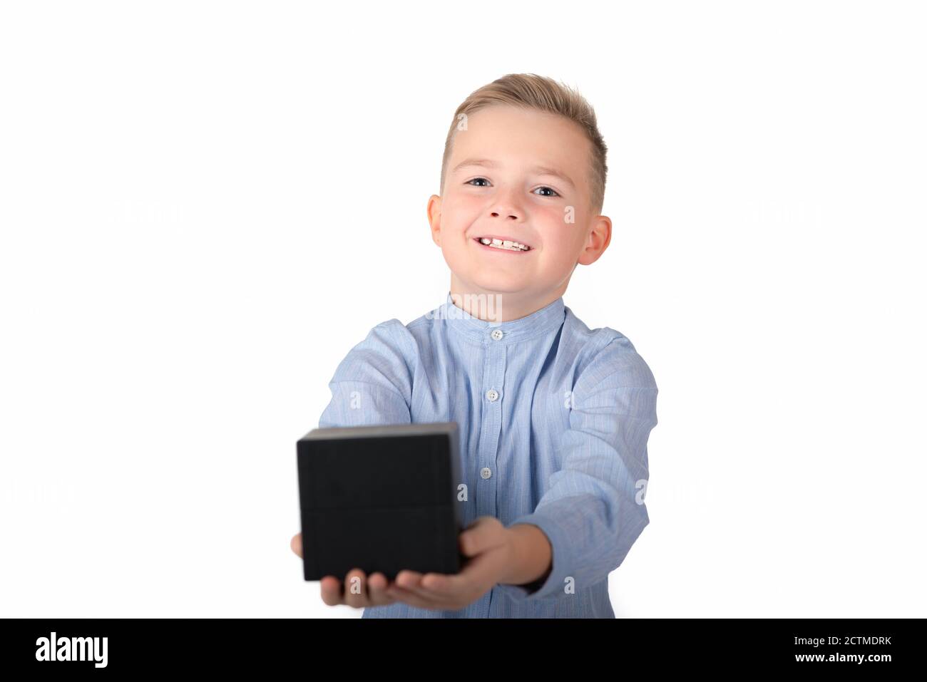 Smiling caucasian blond boy in blue shirt holds black box.the box is in ...