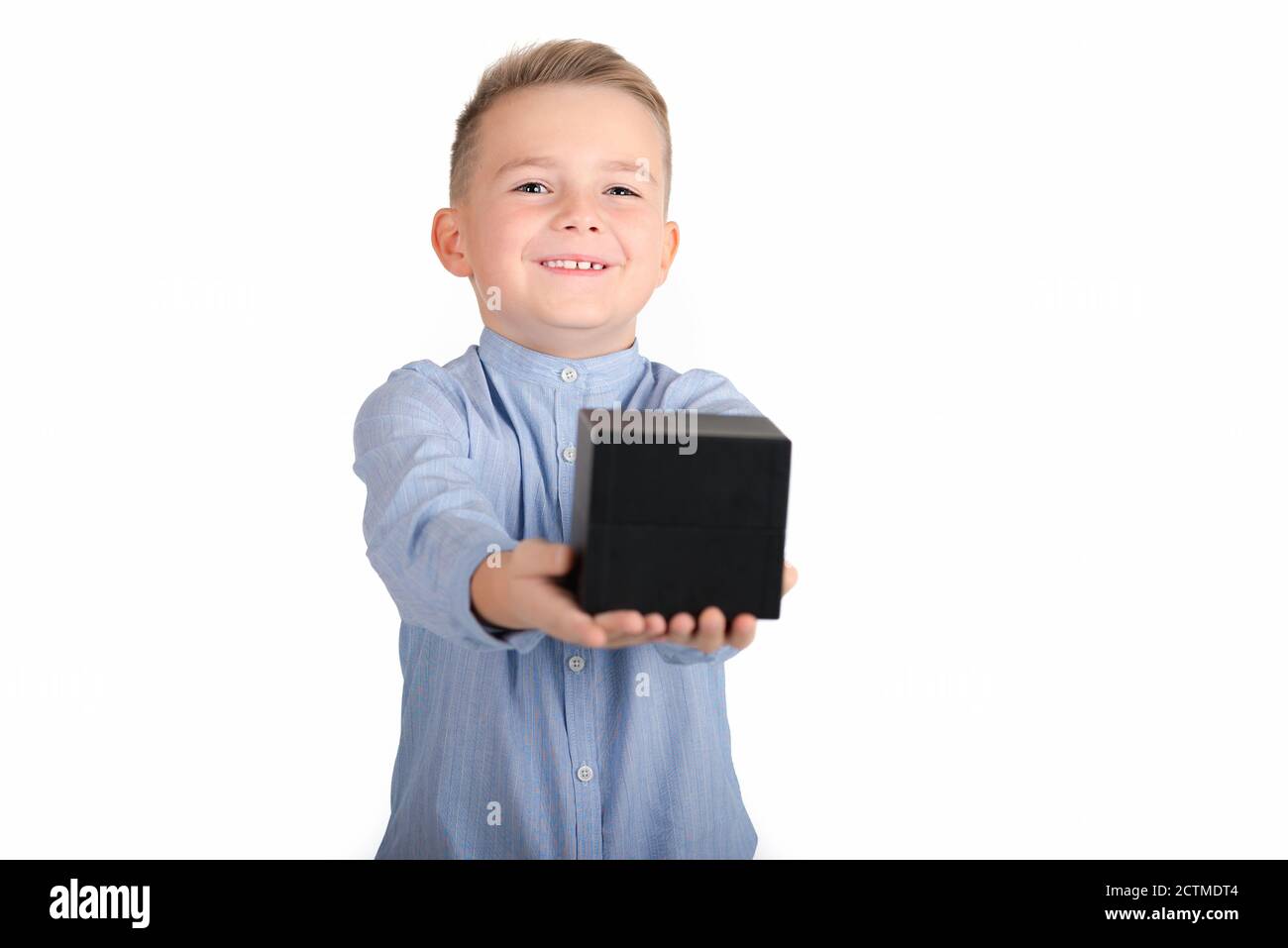 Smiling caucasian blond boy in blue shirt holds black box.the box is in ...