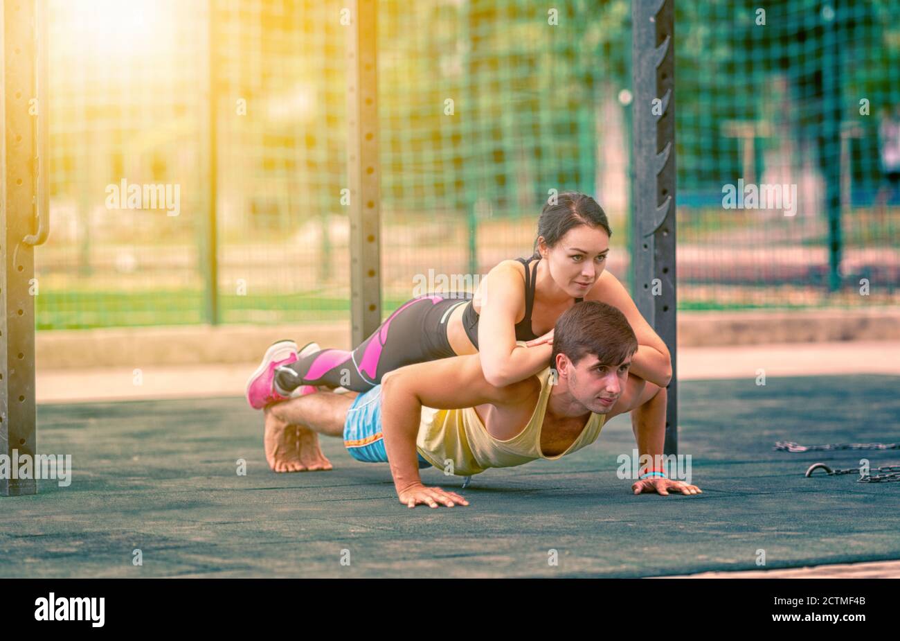 Young couple doing push-ups in tandem with the woman riding on the back ...