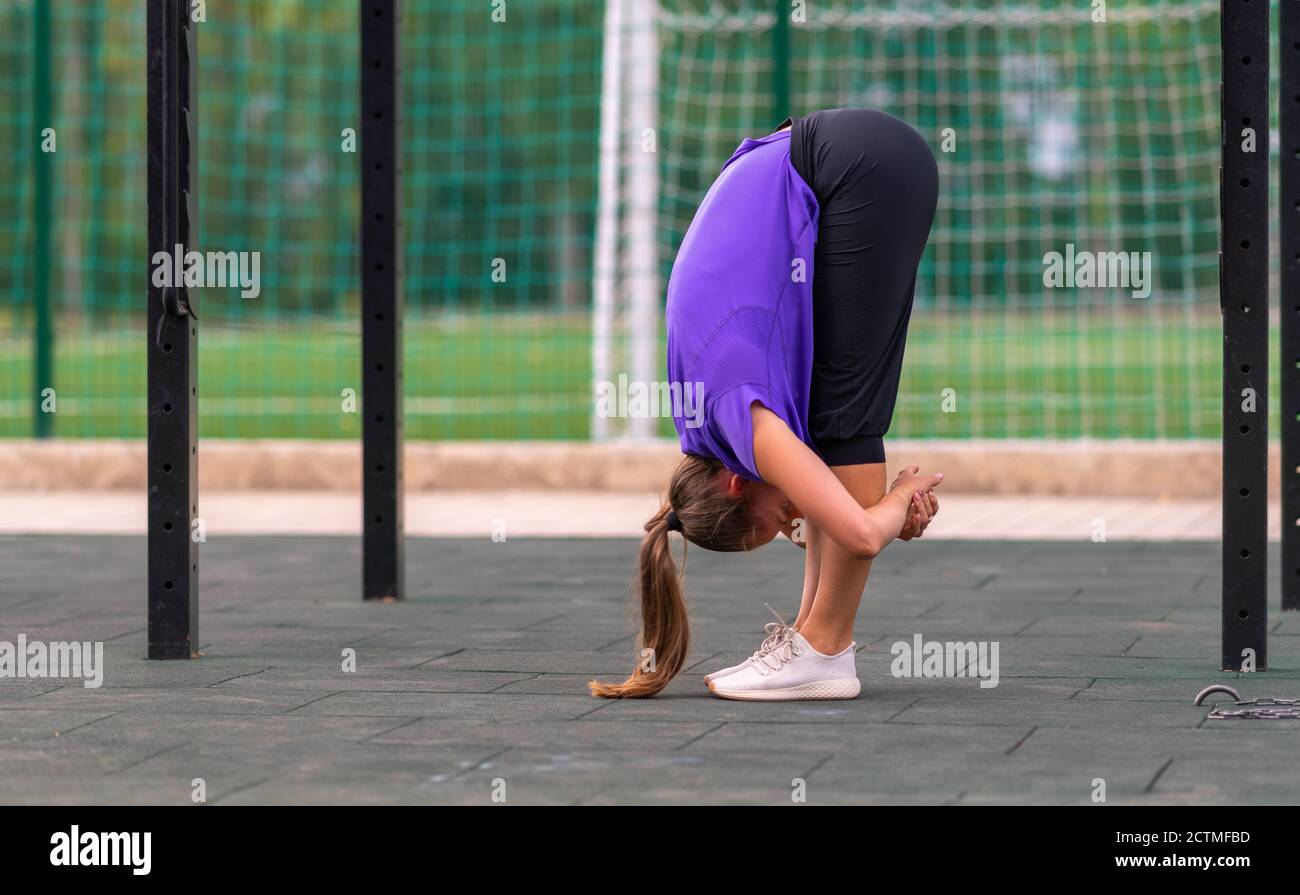 Supple young woman bending double during a workout at an outdoor gym in ...