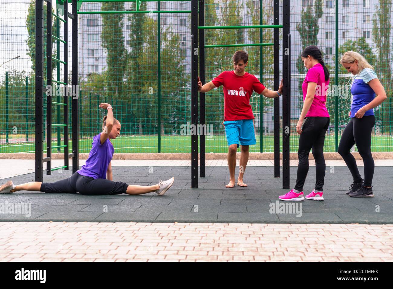 Group of young people working out together at an outdoor gym in a park ...