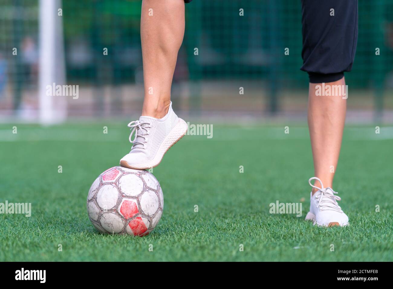 Legs of a muscular young woman with foot on a ball on a green sports ...