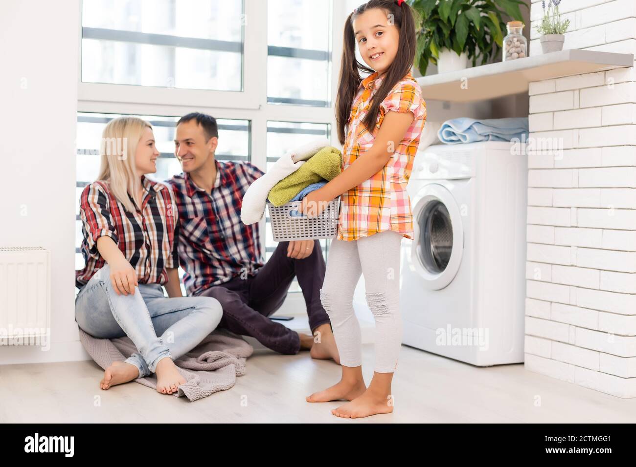 family mother, father and child girl little helper in laundry room near ...
