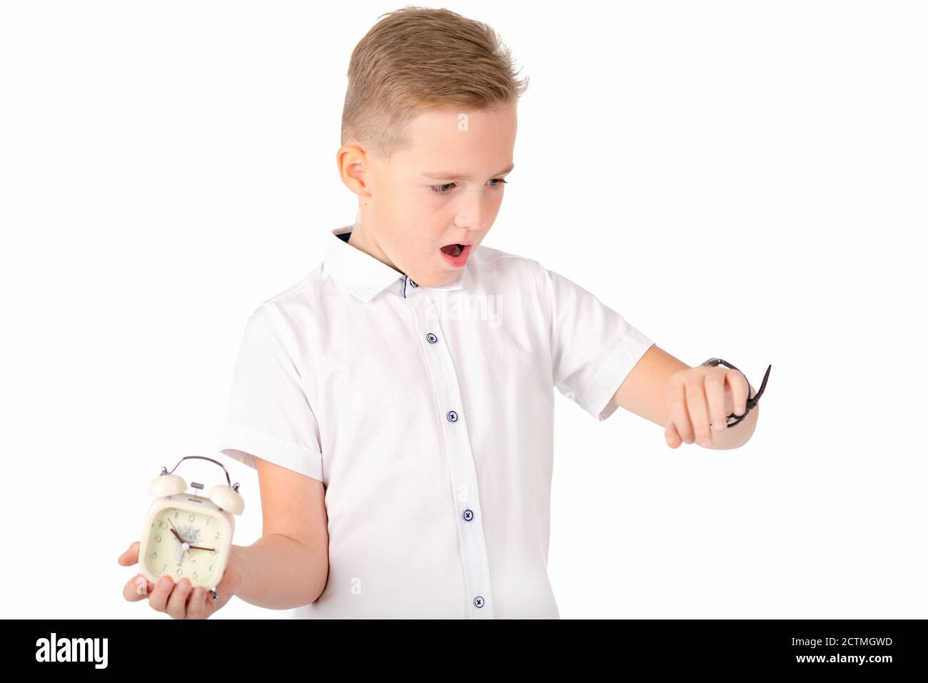 A portrait of surprised cute kid boy holding alarm clock a wristwatch ...