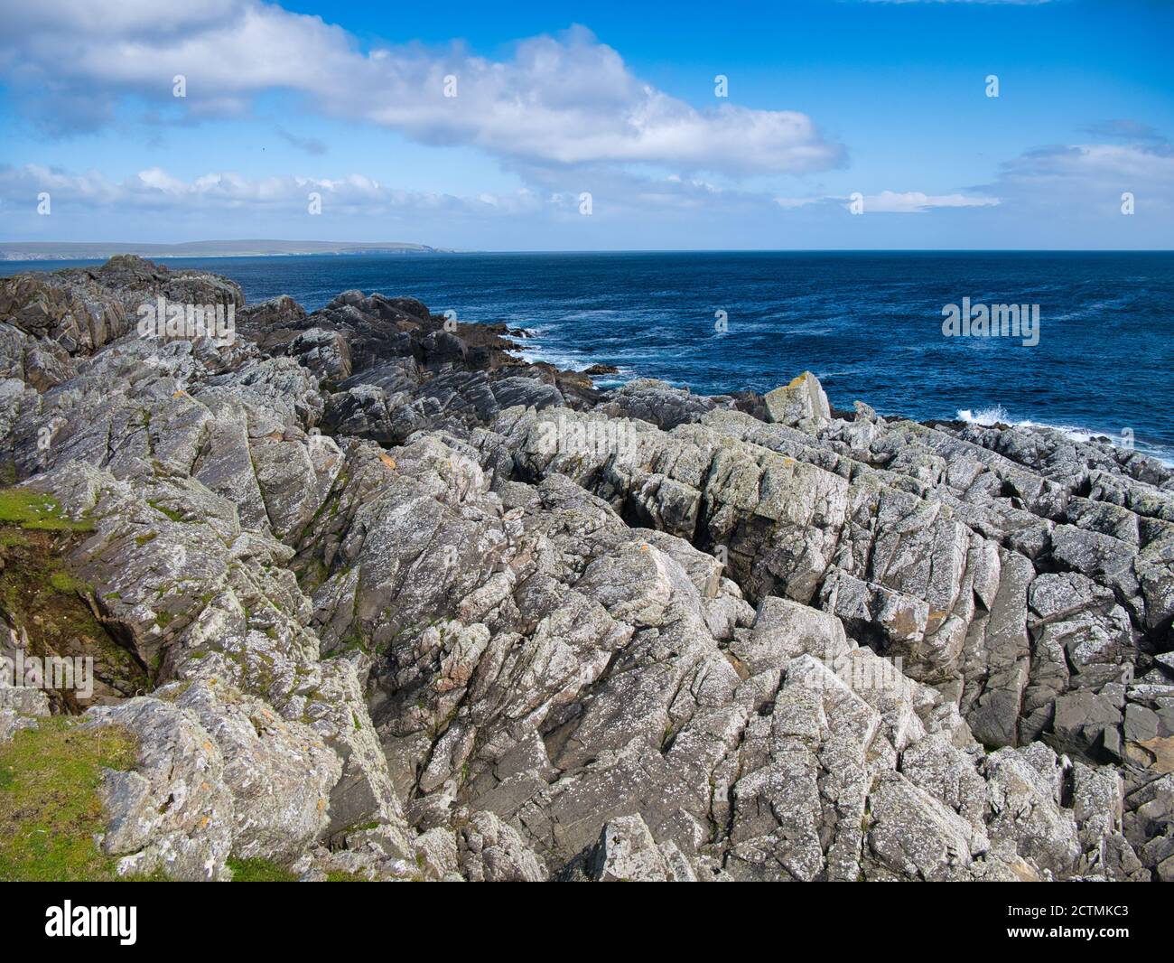 Dramatic coastal scenery showing inclined and eroded rock strata around ...