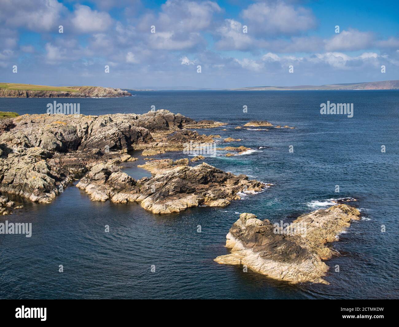 Dramatic coastal scenery showing inclined and eroded rock strata around ...