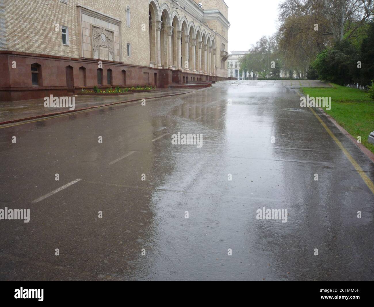 Street in rainy weather near a beautiful architectural building. It's ...
