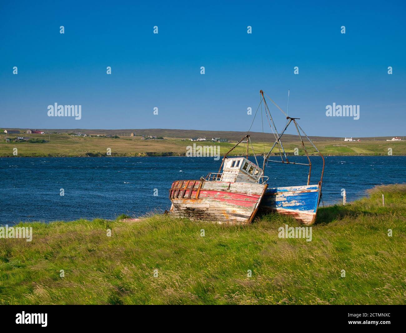 Old, abandoned wooden fishing boats on the shore of Mid Yell Voe at Mid ...