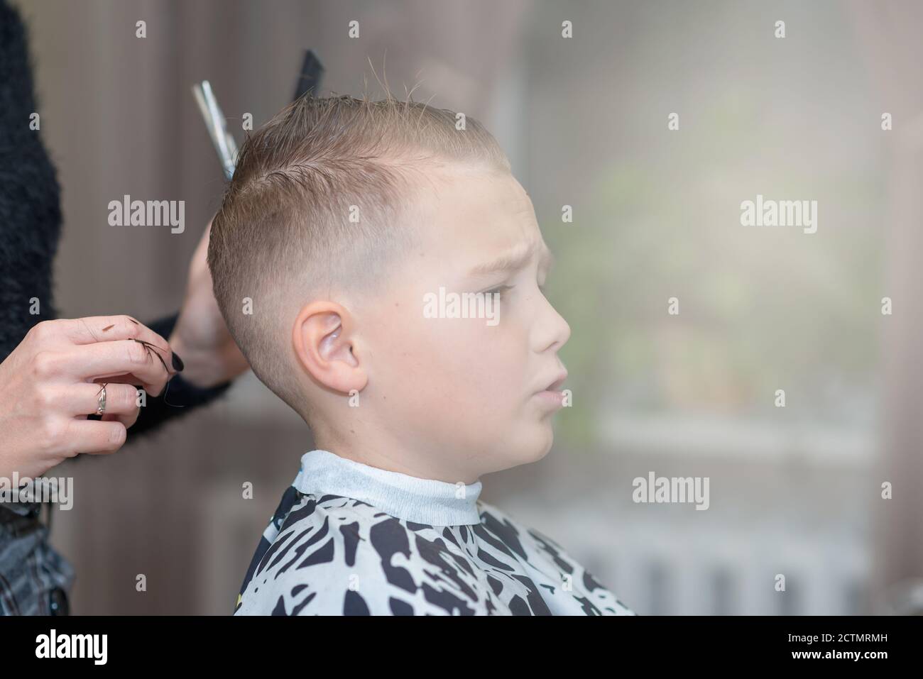 Hairdresser makes a stylish hairstyle. The woman is standing and making ...