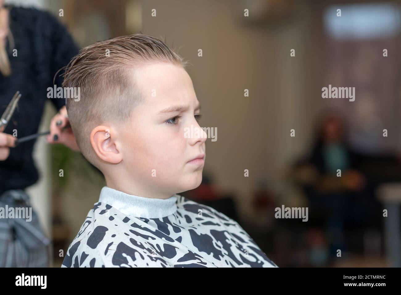 Hairdresser makes a stylish hairstyle. The woman is standing and making ...