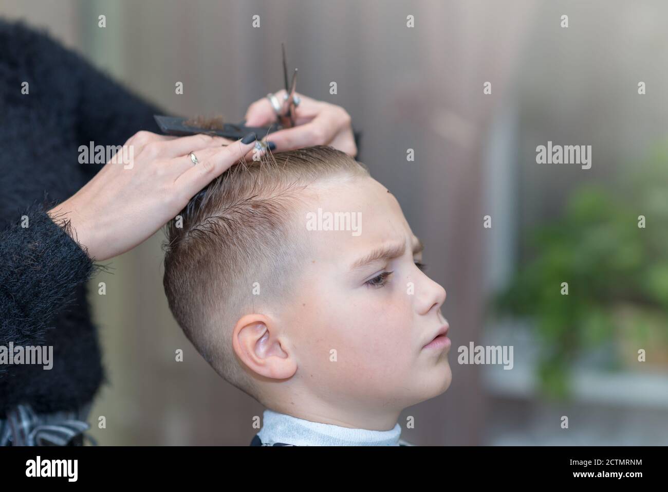 Hairdresser makes a stylish hairstyle. The woman is standing and making ...