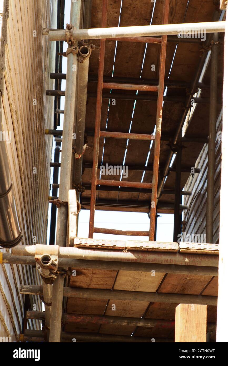 A view looking up from the ground to scaffolding in between two houses ...