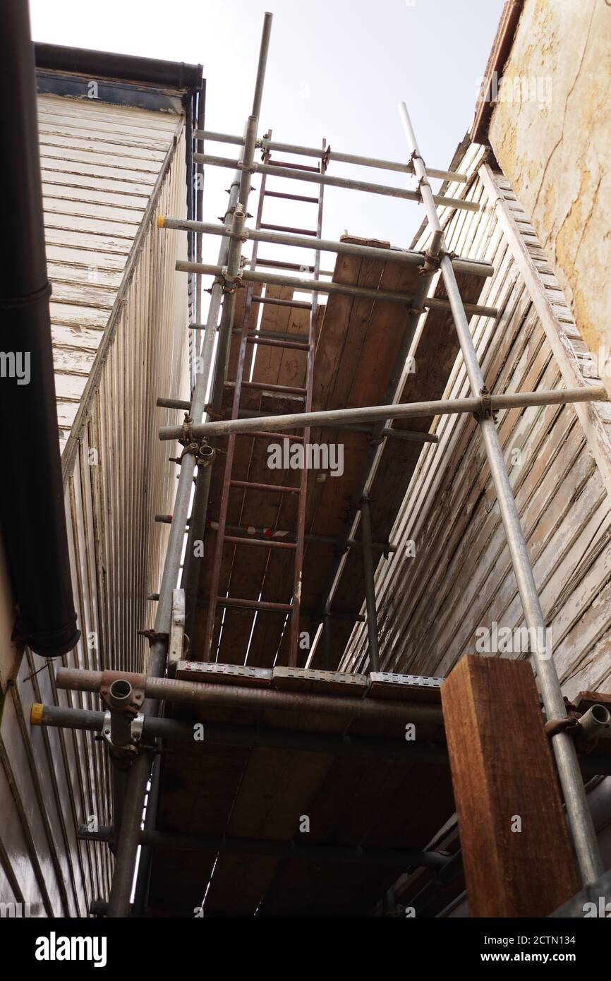 A view looking up from the ground to scaffolding in between two houses ...