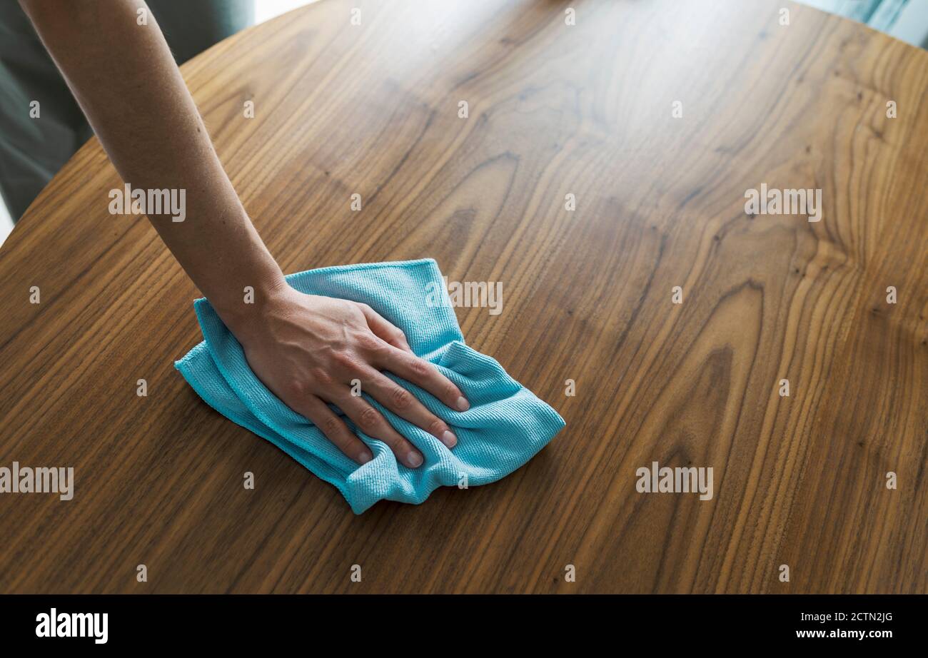 Woman doing housework and cleaning the kitchen table with a cloth ...
