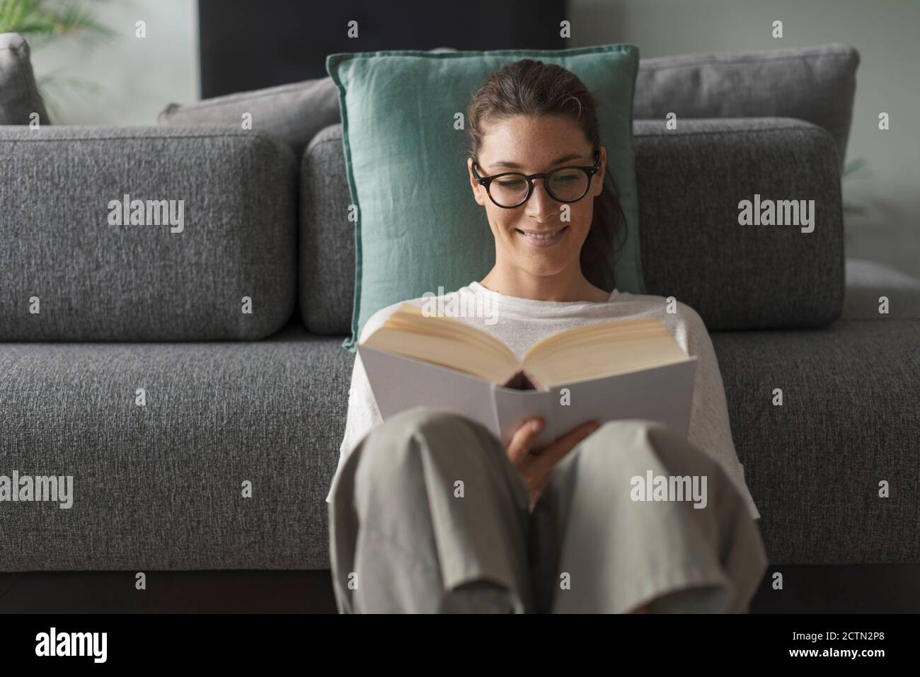 Happy serene woman sitting on the floor and reading a book, she is ...