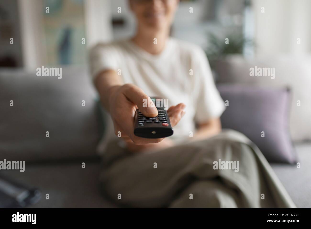Happy woman sitting on the couch and watching television, she is ...